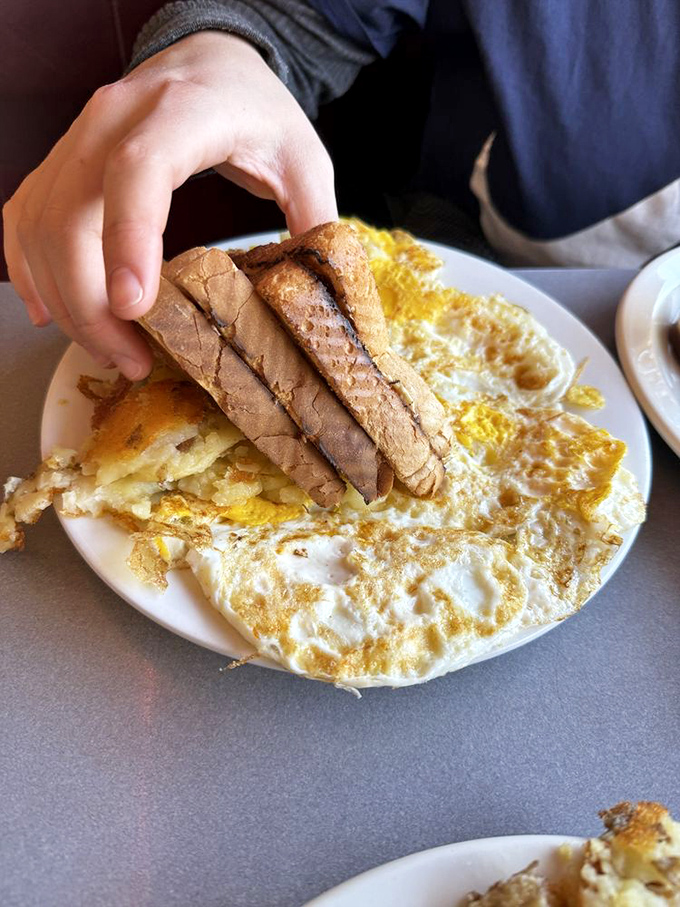The breakfast trinity: golden eggs, crispy bacon, and buttery toast. Simple perfection that's been solving life's problems since the invention of the griddle. 