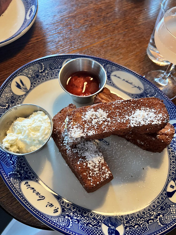 French toast sticks that would make your childhood self high-five your adult self. Crispy, cinnamon-dusted perfection served with cream and jam for dunking delight.