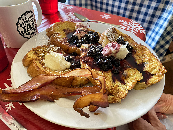 The French toast arrives like a celebrity, surrounded by an entourage of crispy bacon and crowned with a berry compote that steals the show.