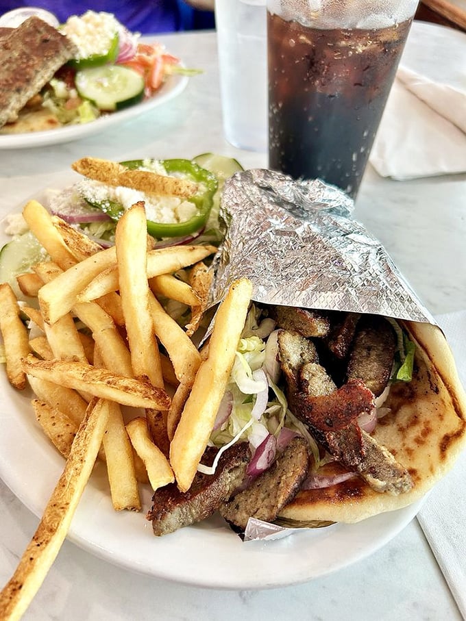 The holy grail of handheld happiness – perfectly seasoned gyro wrapped in pillowy pita with crispy fries standing guard.