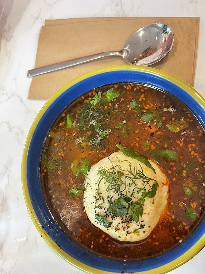 Look at that broth – clear as consommé but deep as philosophy, cradling a matzo ball that's achieved perfect buoyancy and texture.