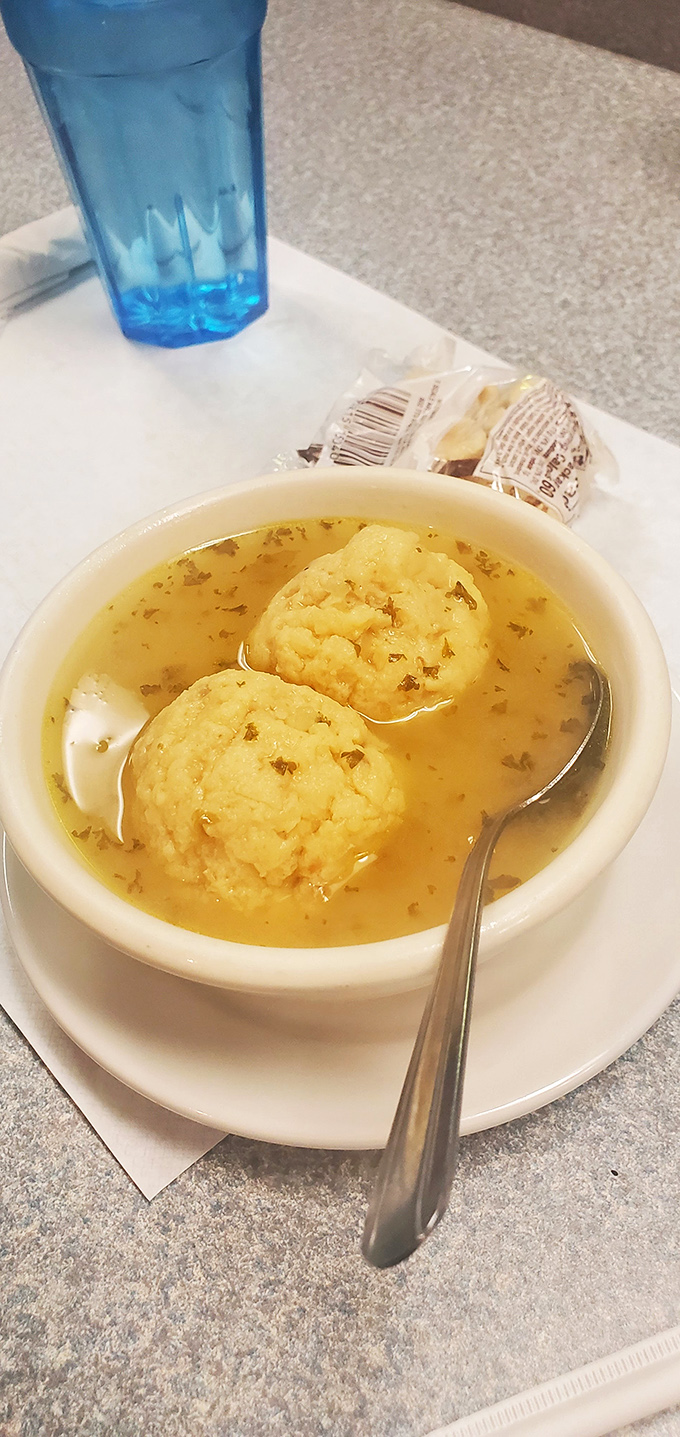 Two perfect matzo balls swimming in chicken broth clearer than your conscience after confession. The crackers are just a bonus.