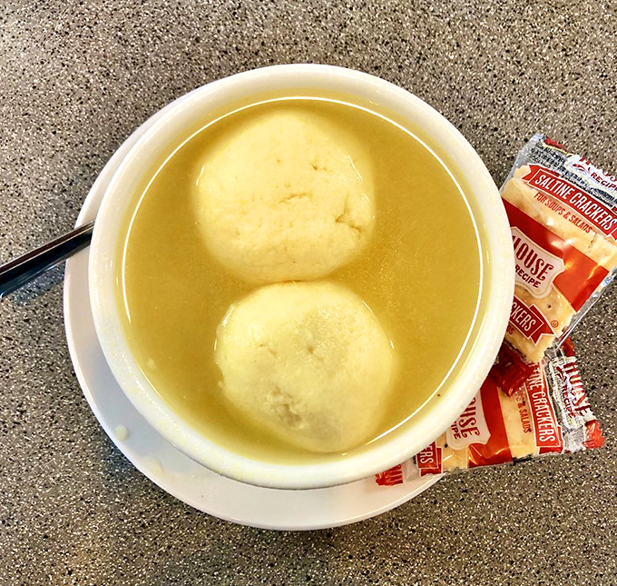 Two perfect matzo balls swimming in liquid gold. This isn't just soup—it's edible therapy in a bowl.