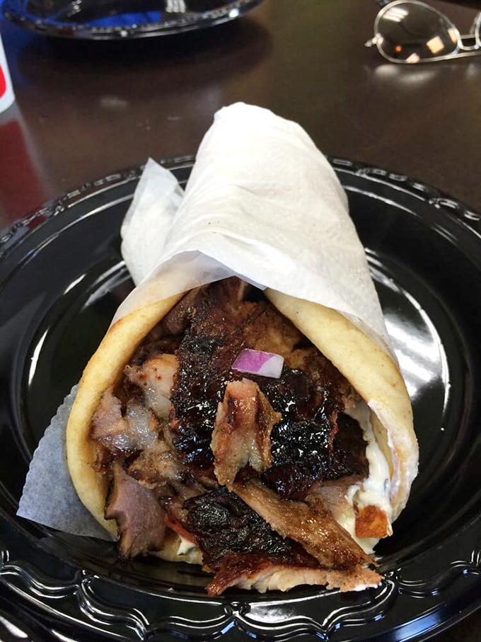 This pork gyro isn't just a sandwich, it's an architectural marvel of crispy-edged meat, creamy sauce, and a pita that somehow contains the delicious chaos.