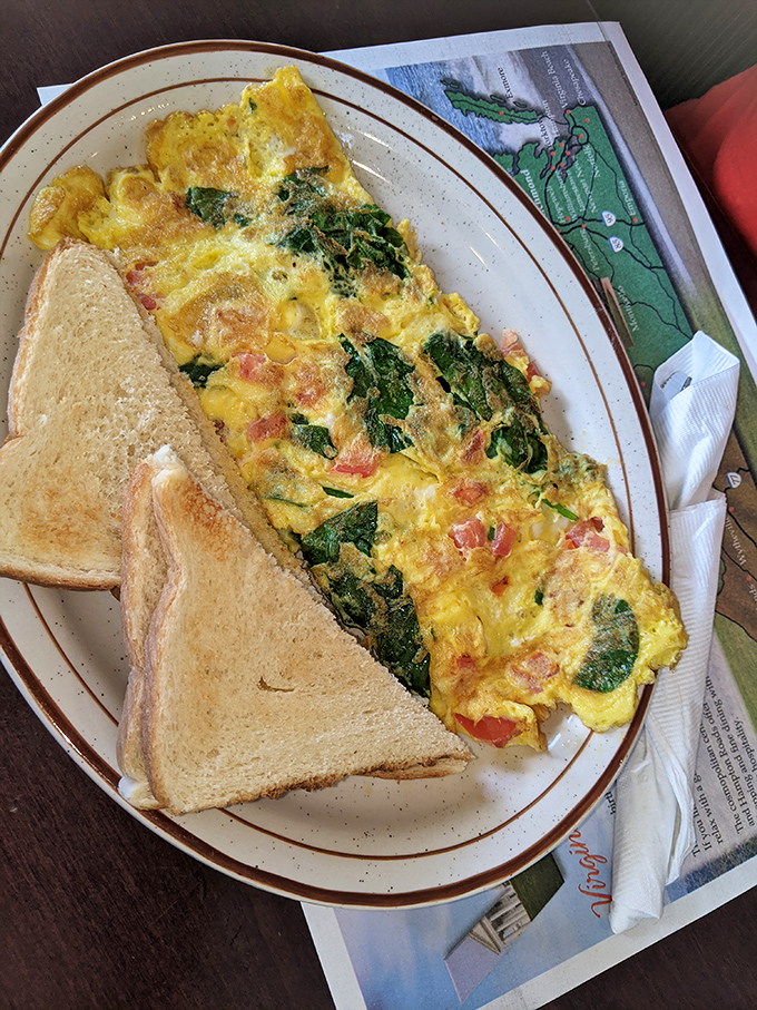 The Spinach Omelet arrives like a yellow canvas painted with vibrant greens and reds. Toast stands by, ready for the supporting role.