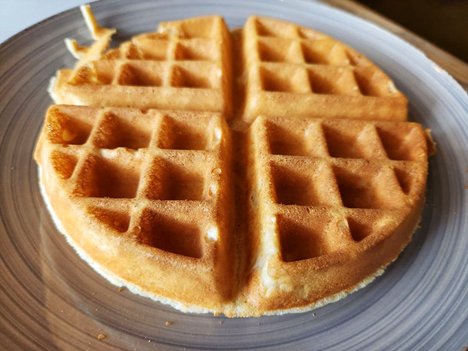 Golden waffle architecture at its finest. Those perfect squares are actually tiny pools waiting for butter and syrup to create breakfast magic.