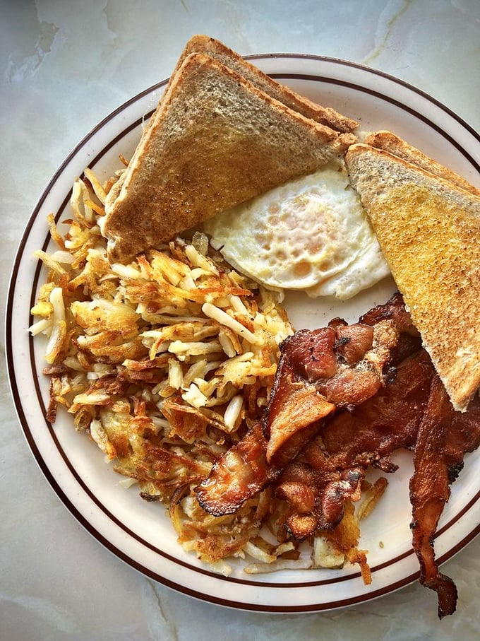 The breakfast trinity—crispy bacon, perfectly fried eggs, and hash browns that somehow manage to be both crispy and tender. Hallelujah!