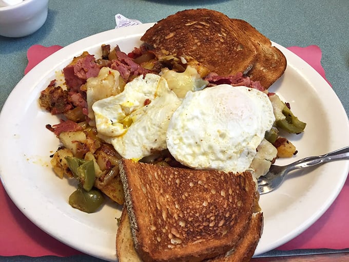 Two sunny-side up eggs keeping watch over a mountain of home fries and toast. The breakfast trinity, executed with diner perfection.