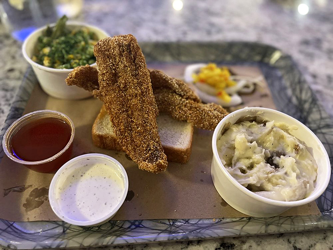 Cornmeal-crusted catfish strips stand tall like crispy sentinels guarding creamy mashed potatoes and verdant collards&mdash;a Southern security detail for your appetite.