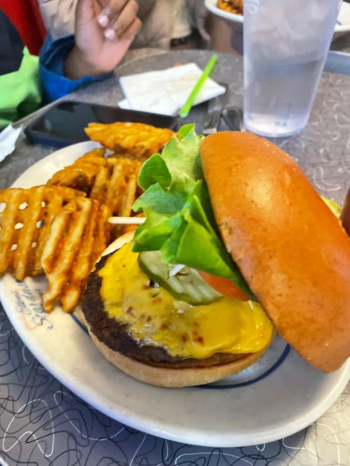 The cheeseburger arrives like the lead actor in a culinary production, with waffle fries playing the essential sidekick role to perfection.