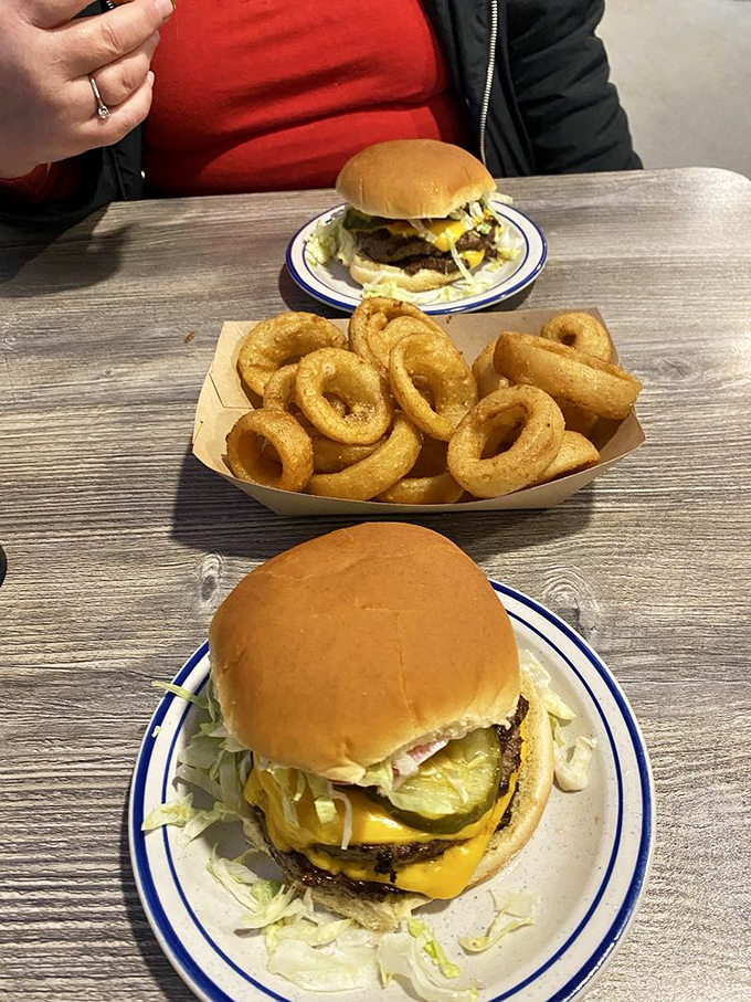The burger trifecta: golden bun, melty cheese, and a basket of onion rings that could make a grown adult weep with joy.