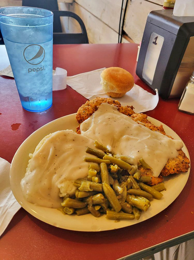 The chicken fried steak arrives like a crispy island in a sea of creamy gravy, with green beans standing by as the token vegetable witness.