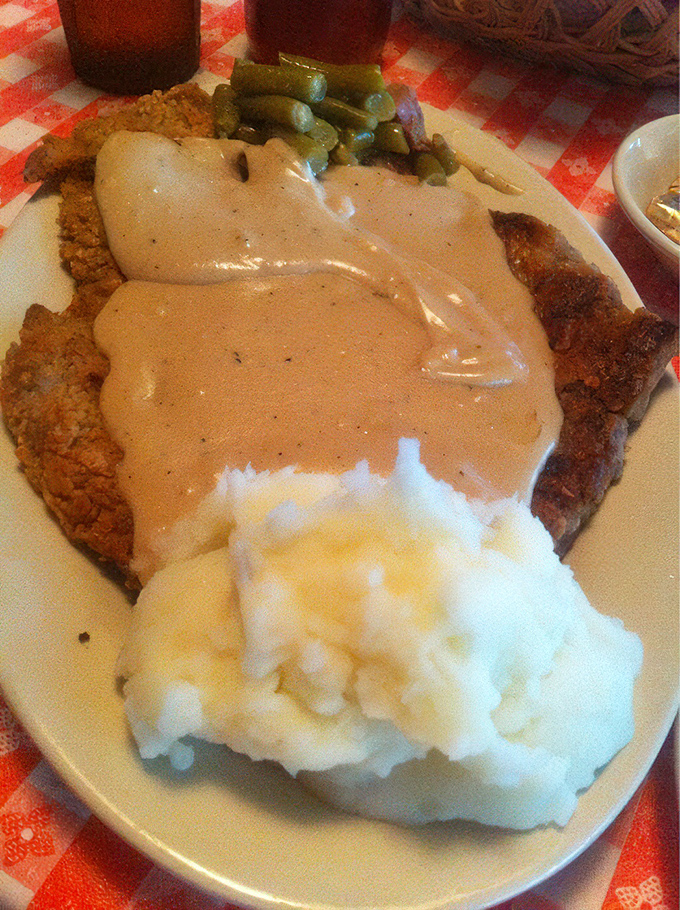 The holy trinity of Midwestern comfort: chicken fried steak blanketed in gravy, cloud-like mashed potatoes, and green beans that have surrendered all pretense of healthfulness.