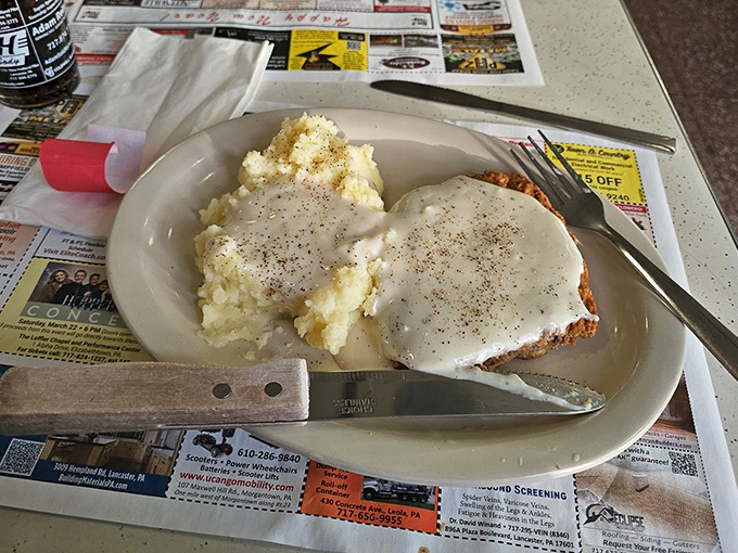 This isn't just country fried steak &ndash; it's a masterpiece of contrasts where crispy golden exterior meets tender meat, all blanketed in gravy that could solve world peace.