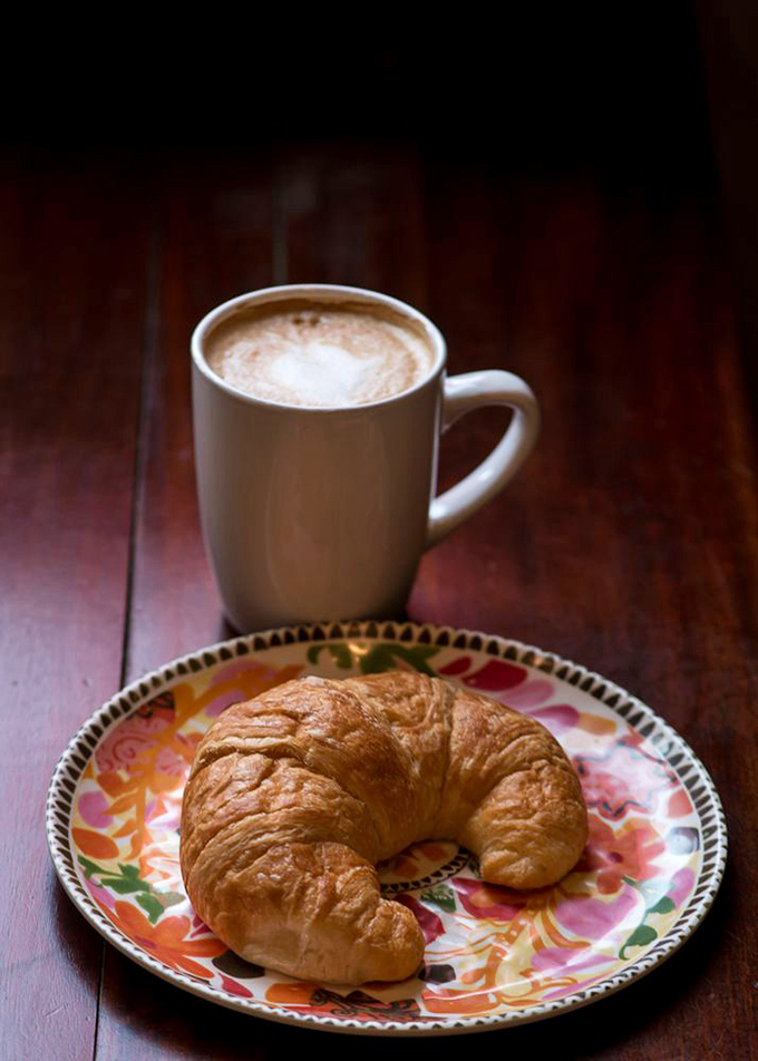 The holy trinity of morning perfection: a buttery croissant, steaming coffee, and a colorful plate that brightens even Monday mornings.