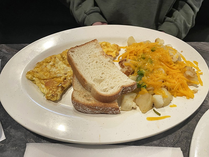 The breakfast trinity: perfectly cooked eggs, hearty toast, and home fries loaded with cheese that stretches with each forkful.