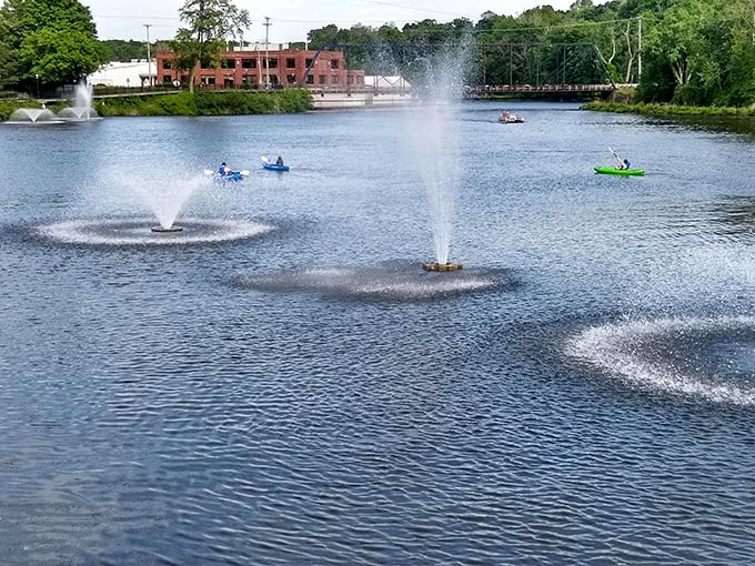 Kayakers paddle through Allegan's riverfront park where fountains create both ambiance and a practical solution to keeping the water moving. Nature and engineering in perfect harmony.