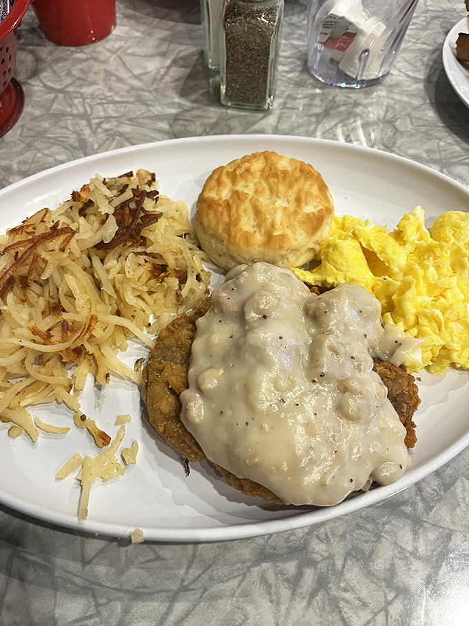 A perfect trifecta: crispy country fried steak, creamy homemade gravy, and a biscuit that's begging to sop up every last drop.