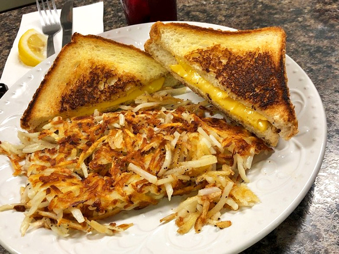 Behold the grilled cheese sandwich in its natural habitat, flanked by the crispy hash browns that have launched a thousand road trips
