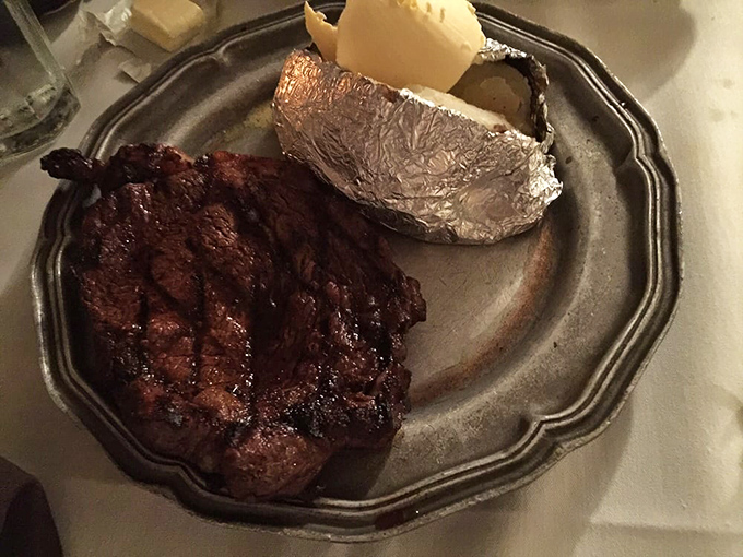 This ribeye isn't just cooked &ndash; it's been coaxed to perfection, developing the kind of crust that makes steak lovers weak at the knees. The foil-wrapped potato stands by, ready for its moment.