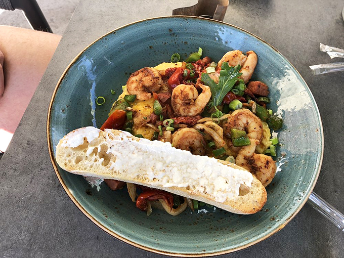 Plump shrimp nestled in creamy grits with colorful vegetables and a slice of bread for sauce-mopping&mdash;breakfast architecture at its finest.