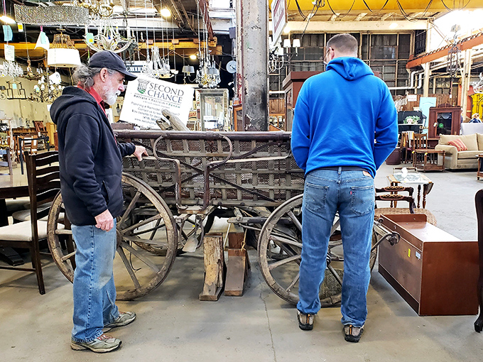 Treasure hunters examining an antique cart, mentally measuring whether it would fit in their living room or just in their dreams.