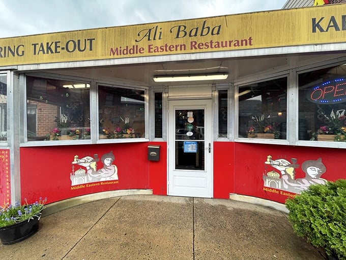 Ali Baba's vibrant red storefront stands out like a ruby, its Middle Eastern artwork promising exotic flavors within this Newark treasure.