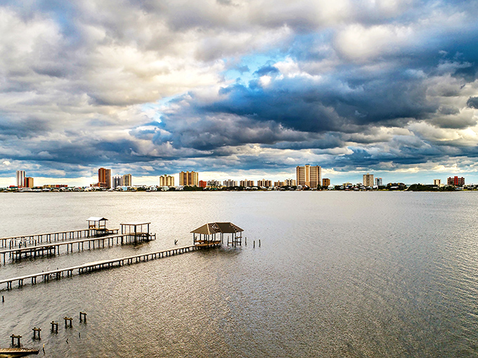 The tranquil waters of Gulf Shores reflect dramatic clouds, showcasing why this affordable coastal gem attracts sun-seekers on a budget.