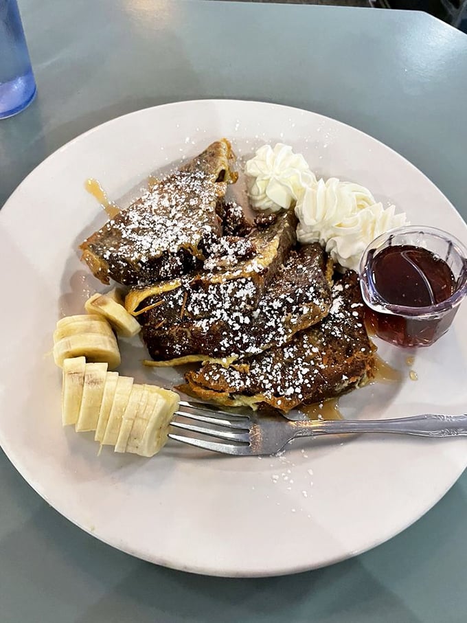 Banana slices standing at attention beside French toast that's been blessed by maple syrup. The whipped cream is just showing off at this point.