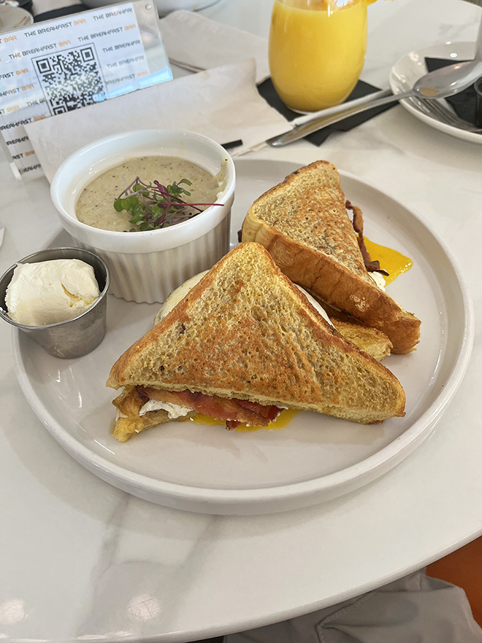 The breakfast sandwich—humanity's greatest invention after fire and indoor plumbing—executed with golden-brown precision and a side of creamy grits.