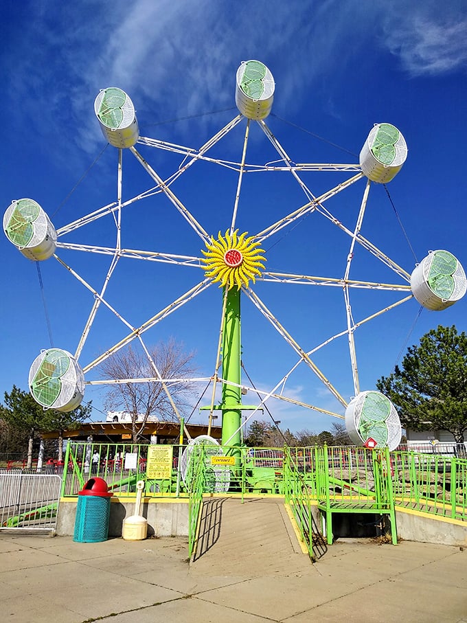 The Ferris wheel's cheerful green frame and sunny yellow center brighten even cloudy Kansas days, offering riders a gentle ascent into childhood nostalgia.