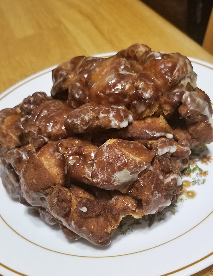 Behold the apple fritter in its natural habitat - a masterpiece of fried dough that's worth every calorie and minute in line. 