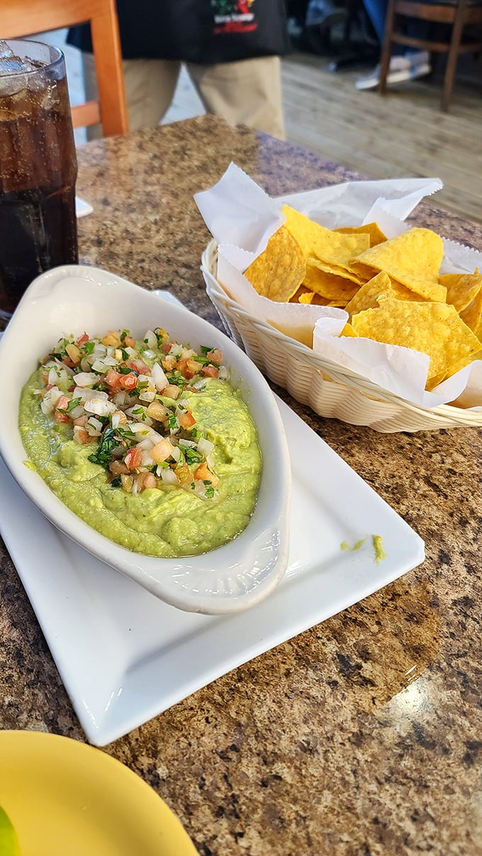 Fresh guacamole topped with pico de gallo next to perfect chips&mdash;the kind that make you forget your promise to "just have one" faster than you can say "refill."
