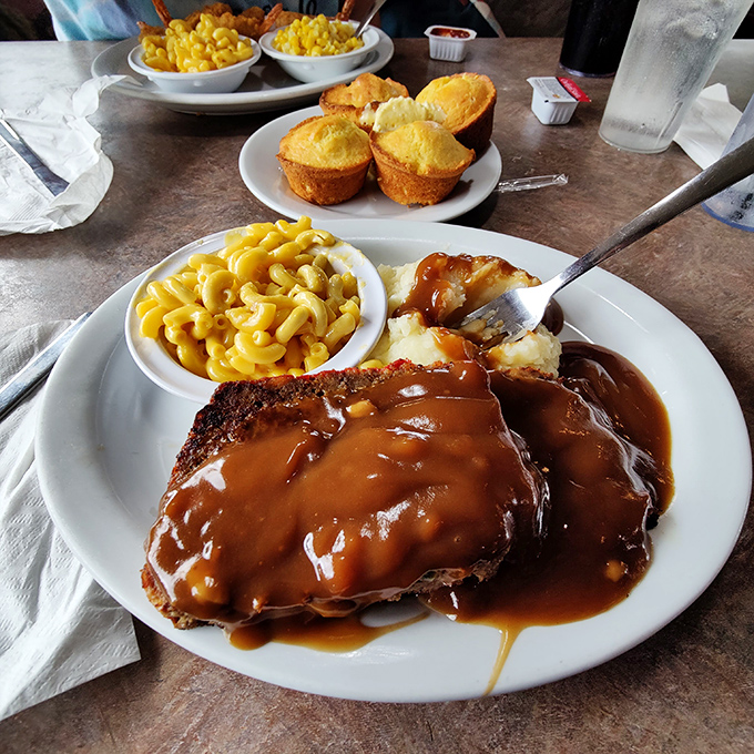 Meatloaf swimming in rich brown gravy with mac and cheese and cornbread muffins. This isn't just comfort food&mdash;it's therapy on a plate without the hourly rate.