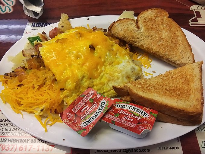 Breakfast architecture at its finest: a precisely constructed omelet flanked by crispy hash browns and toast soldiers ready for yolk-dipping duty.