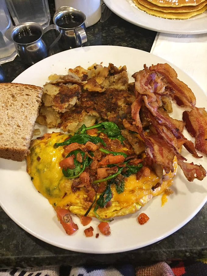 Breakfast trinity: golden omelet, crispy home fries, and bacon cooked to perfection. The holy grail of morning meals has been found.