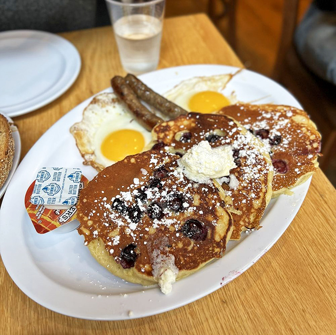 Pancakes dusted with powdered sugar, served alongside sunny-side-up eggs and sausage&mdash;breakfast's greatest hits album on a single plate.