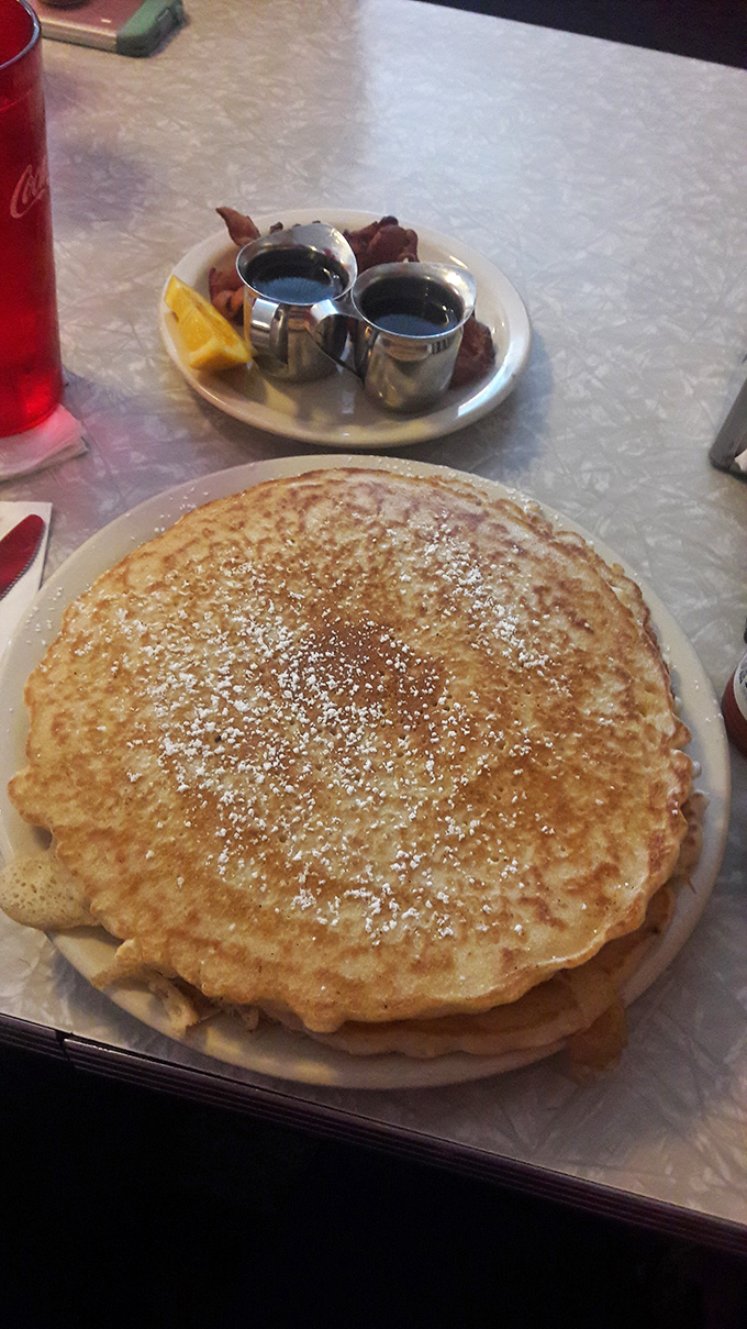A pancake so perfectly golden it deserves its own Instagram account, flanked by syrup soldiers standing at attention.