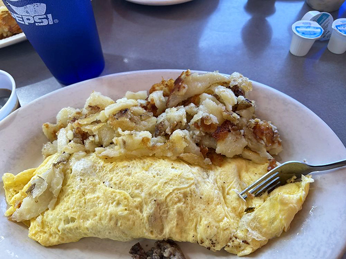 Breakfast ambition realized: sausage links and bacon flanking a fluffy omelet with home fries. The kind of plate that requires a nap afterward&mdash;and zero regrets. 