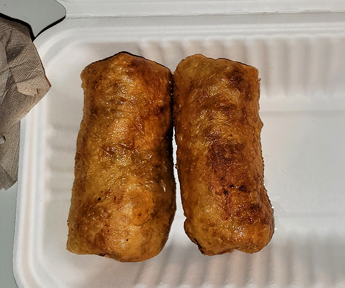 Two perfectly fried bundles of joy sitting pretty in their to-go container – the chimichanga equivalent of "dressed for success" in their crispy formal wear.