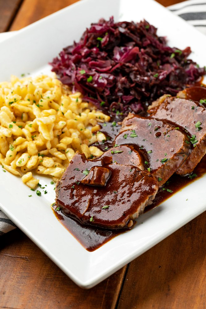 Sauerbraten: where patience becomes flavor. Fork-tender beef bathes in a rich gravy alongside sp&auml;tzle and red cabbage &ndash; Germany's holy trinity.