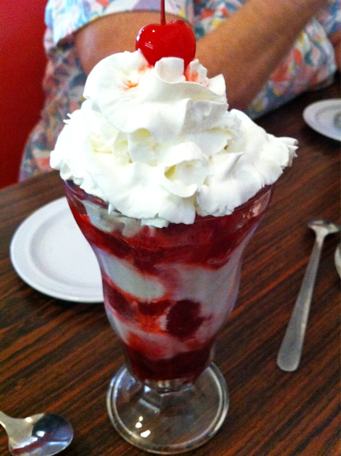 The strawberry sundae here isn't just red and white—it's summer captured in a glass, topped with a cherry that looks like it's keeping watch.