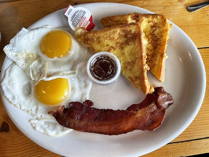 Two sunny-side up eggs flanking crispy bacon and golden toast&mdash;the breakfast equivalent of a perfect high five to start your day right.