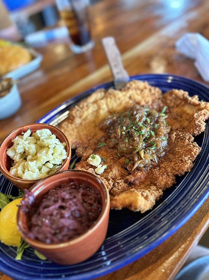 Behold the Wiener Schnitzel in its natural habitat: gloriously golden, sprawled across a blue plate with little pottery cups of accompaniments standing guard.