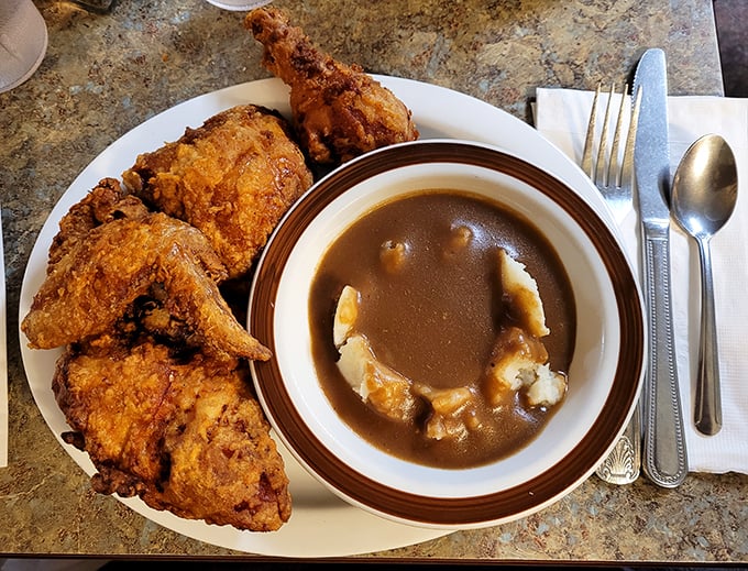 Fried chicken so golden it deserves its own trophy, alongside mashed potatoes swimming in gravy deep enough to require a lifeguard.