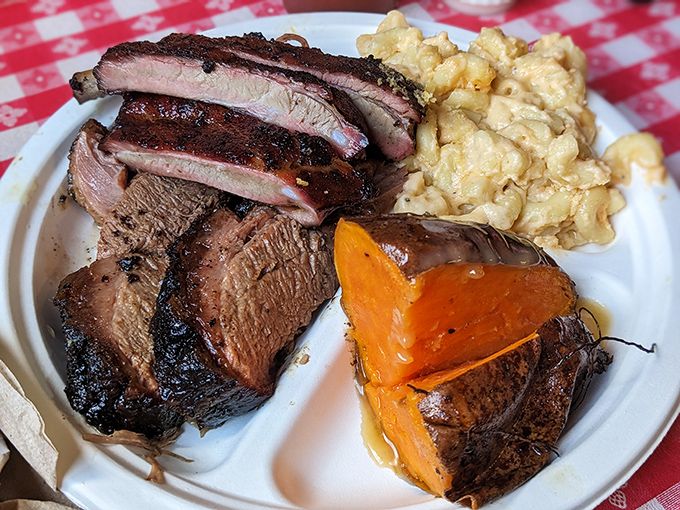 Meat and sides in perfect harmony, like a well-rehearsed barbecue symphony. That sweet potato looks like it's been kissed by smoke angels