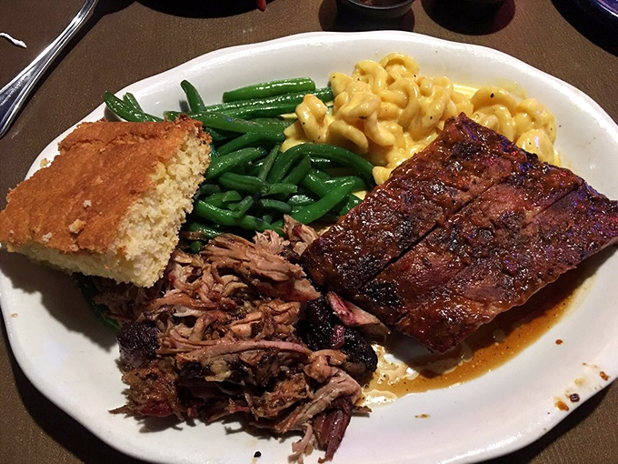 The holy trinity of barbecue: pulled pork, ribs, and all the fixings. This isn't a meal; it's a pilgrimage to the church of smoke. 