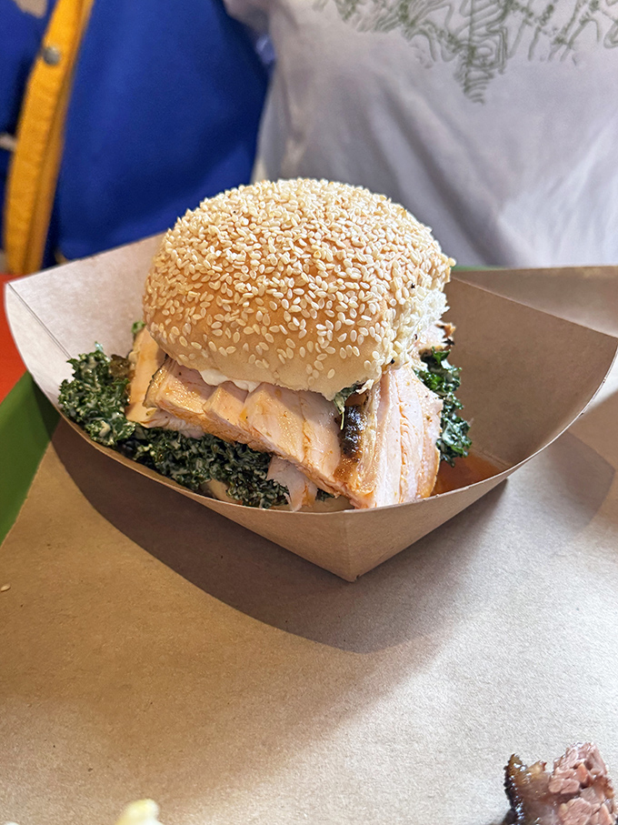 This isn't just a sandwich; it's architecture. Layers of smoked meat and greens on a sesame bun create the Taj Mahal of lunch options.