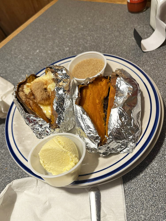 Baked potatoes wrapped like precious gifts from the comfort food gods. The butter cup on the side isn't a suggestion&mdash;it's an invitation to indulgence.