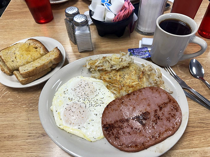 The holy trinity of breakfast: perfectly cooked eggs, crispy hash browns, and a slice of ham that knows exactly what it's doing.